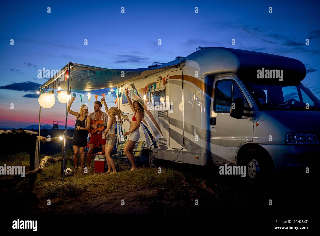 Fun with friends in camp, in front of rv. Young group of people dancing ...