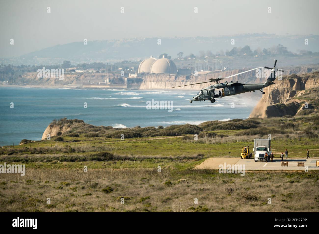 US Navy MH60S flys between a supply ship and the shoreline by Camp ...