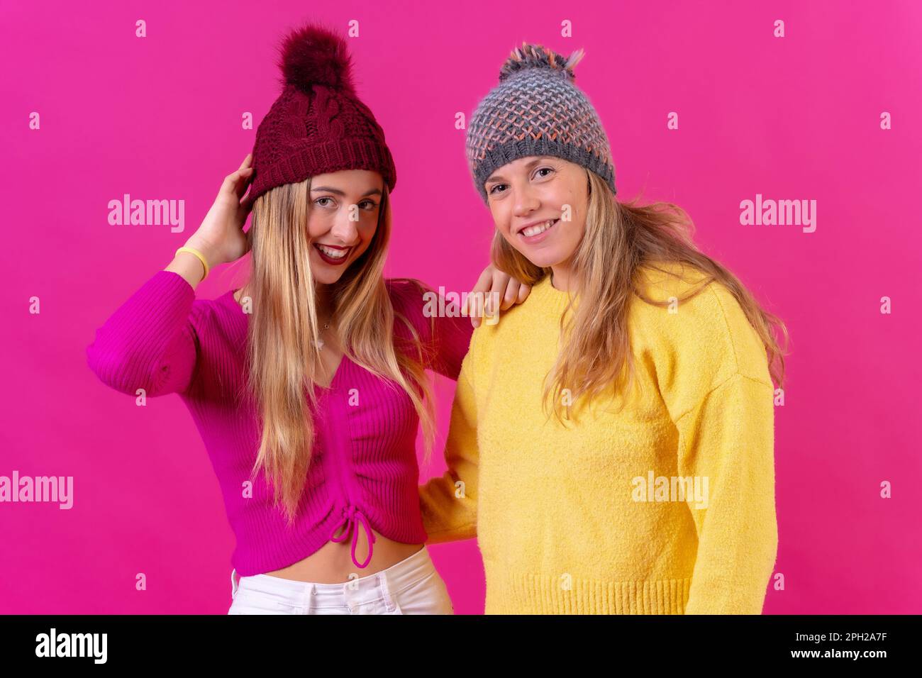 Two females with hats and colorful blouses hugging each other isolated ...