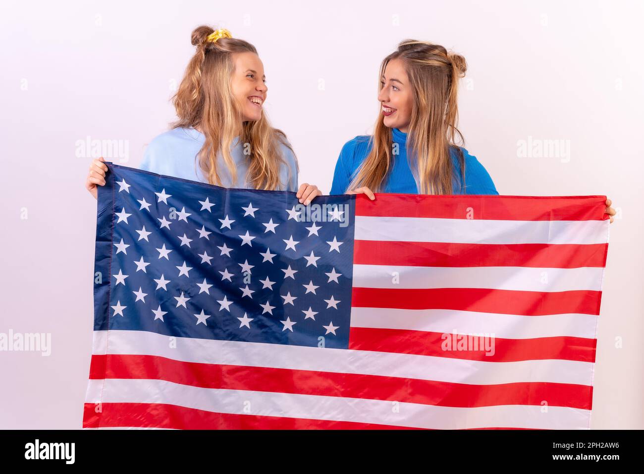 Two smiling females friends proudly displaying the American flag while ... Two smiling females friends proudly displaying the American flag while ...