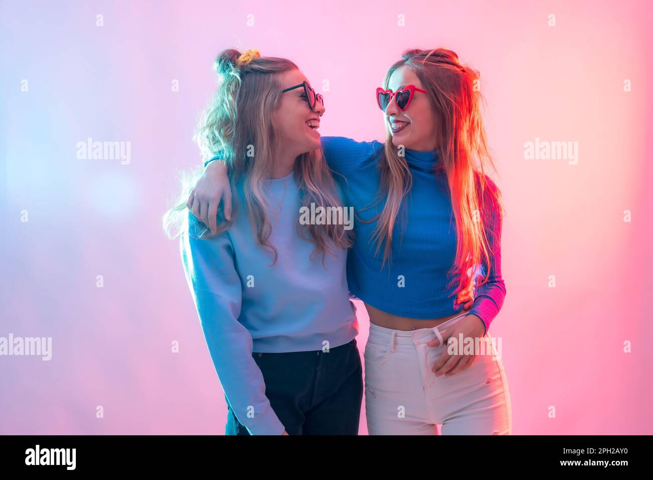 Two females embracing in a warm hug illuminated by bright neon lights ...