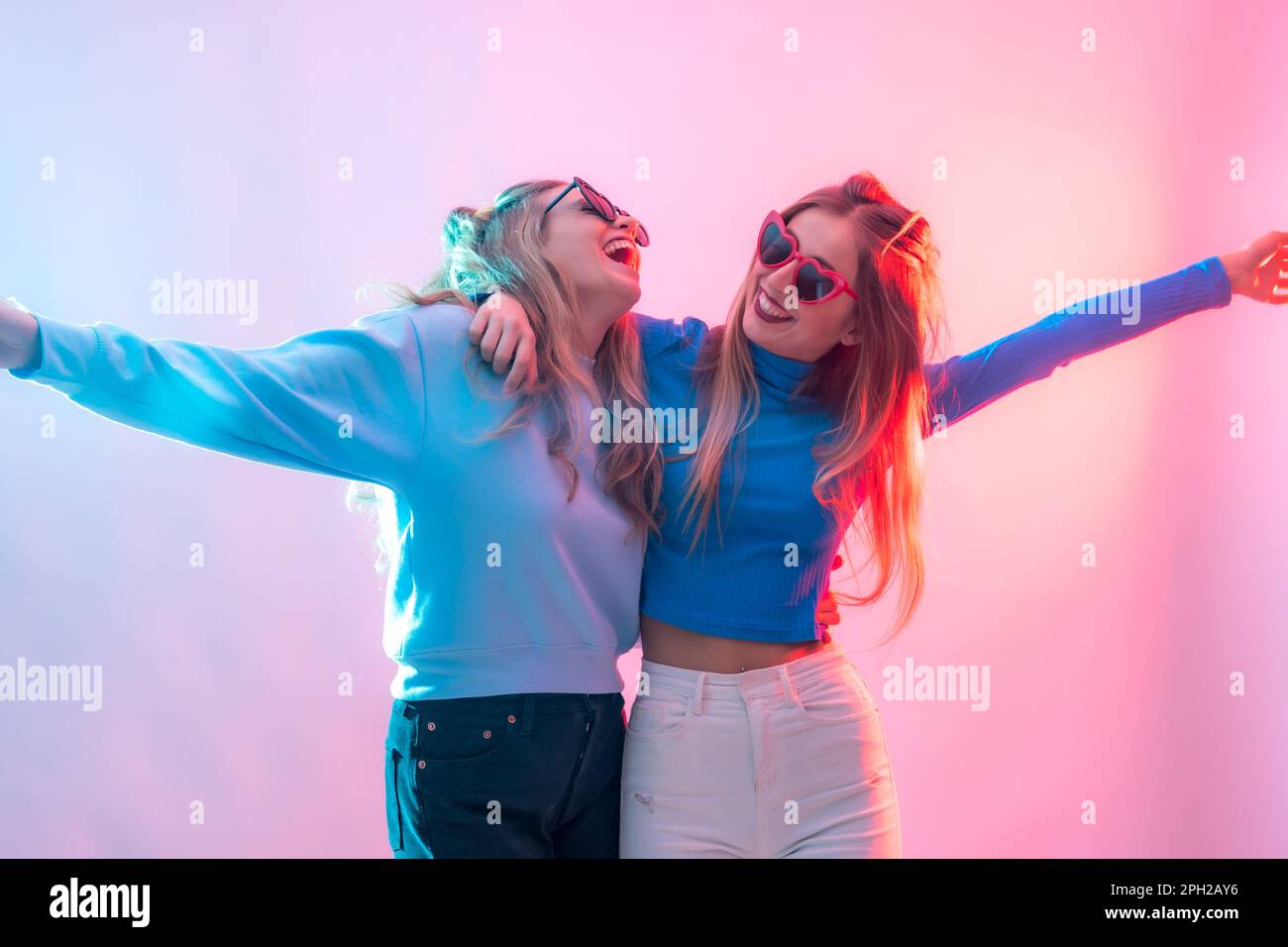 Two females embracing in a warm hug illuminated by bright neon lights ...