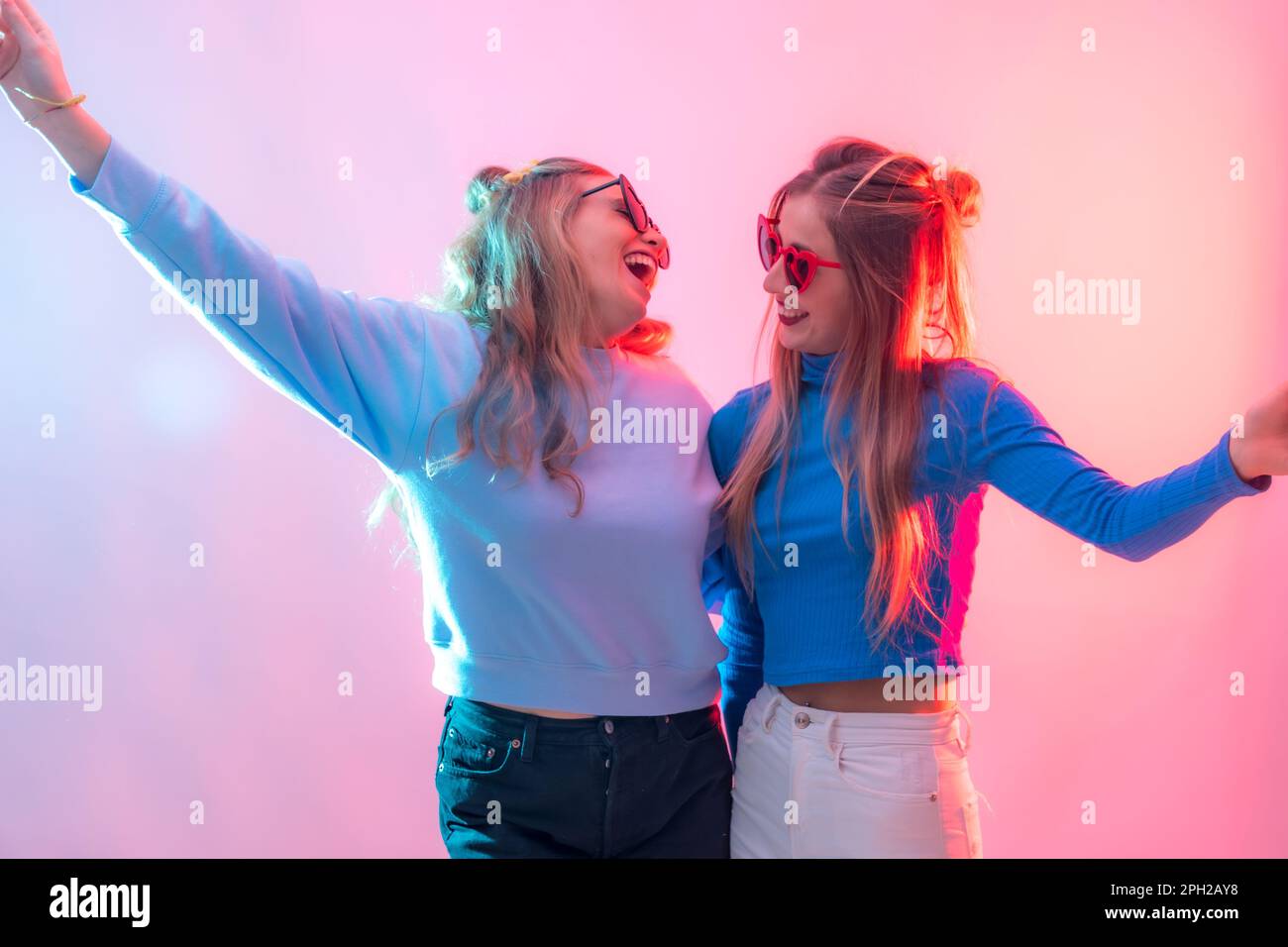 Two females embracing in a warm hug illuminated by bright neon lights ...