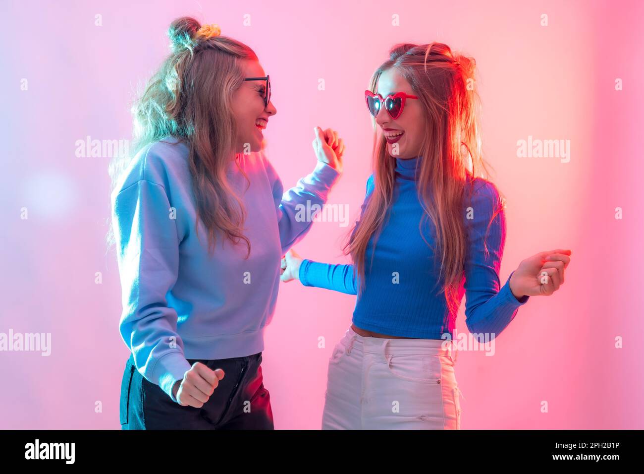 Two females embracing in a warm hug illuminated by bright neon lights ...