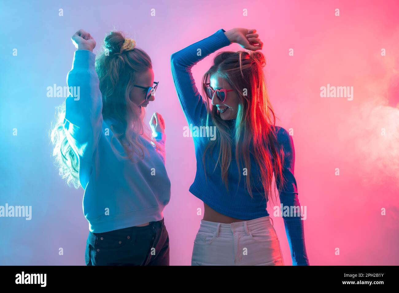 Two females embracing in a warm hug illuminated by bright neon lights ...