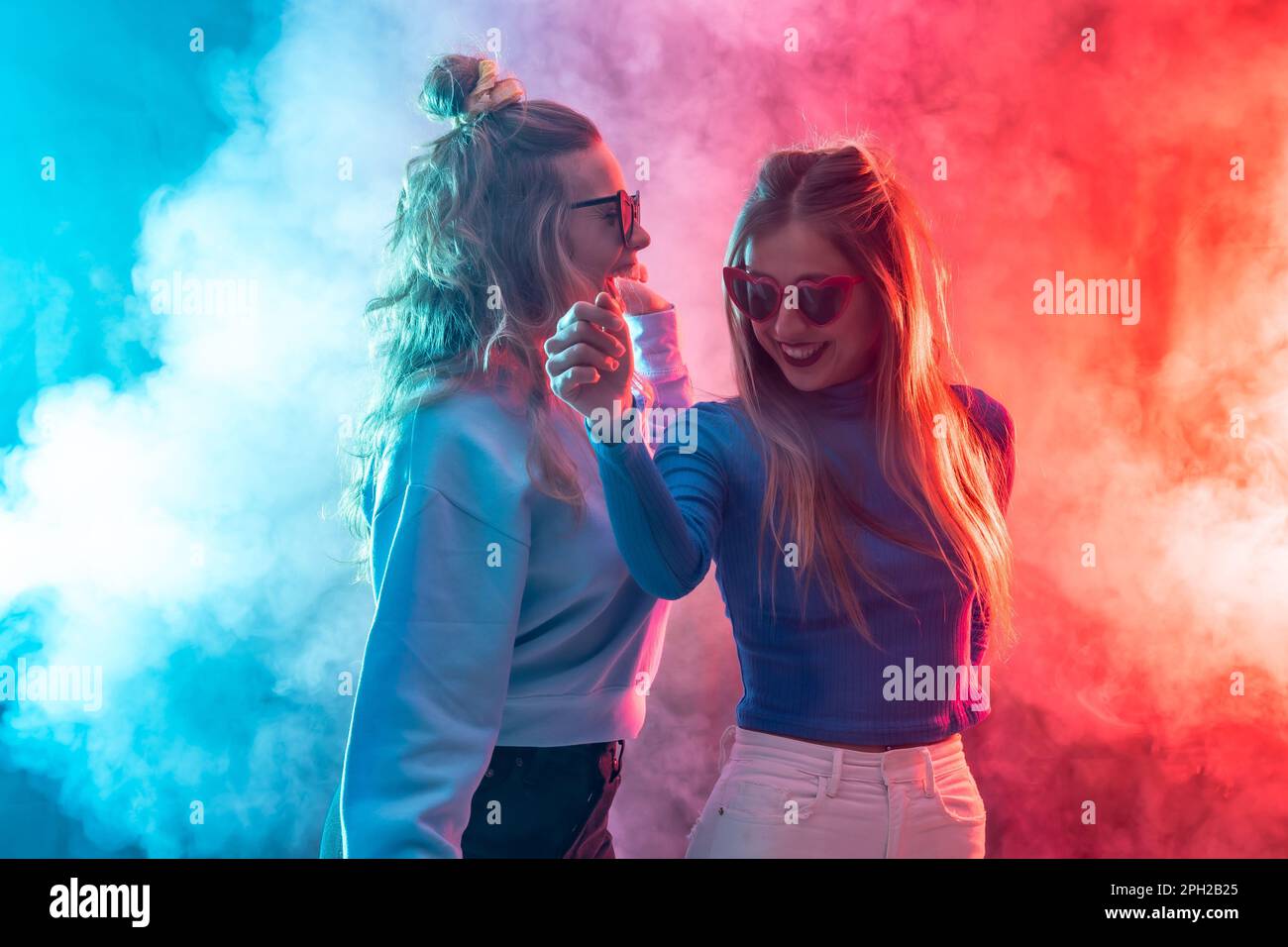 Two females embracing in a warm hug illuminated by bright neon lights ...