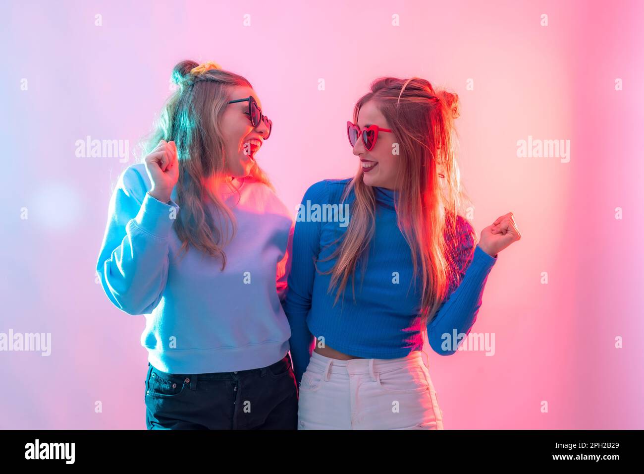 Two females embracing in a warm hug illuminated by bright neon lights ...