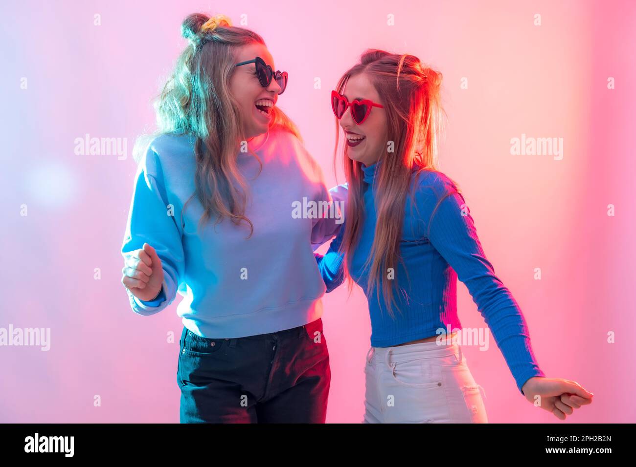 Two females embracing in a warm hug illuminated by bright neon lights ...