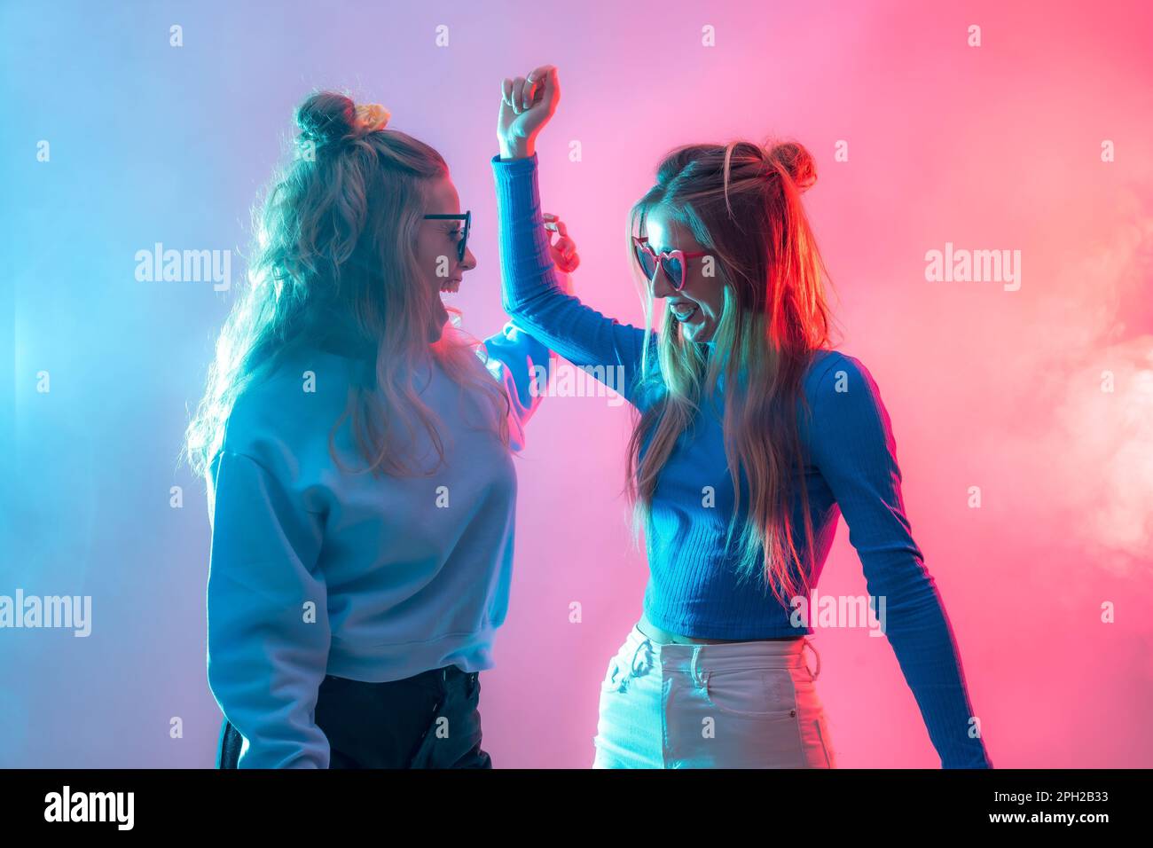 Two females embracing in a warm hug illuminated by bright neon lights ...