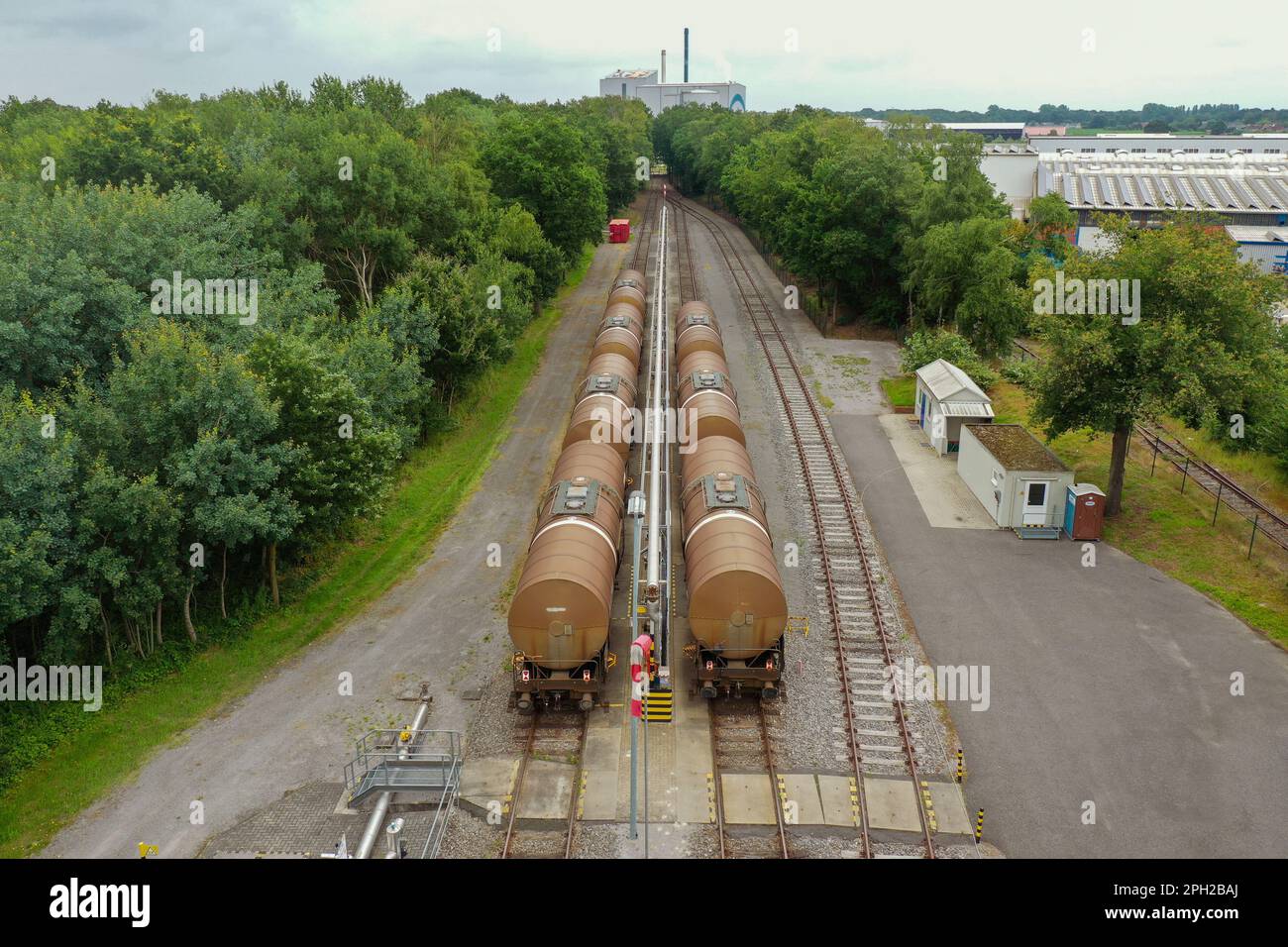 A row of railway carriages parked on a track in an industrial setting ...