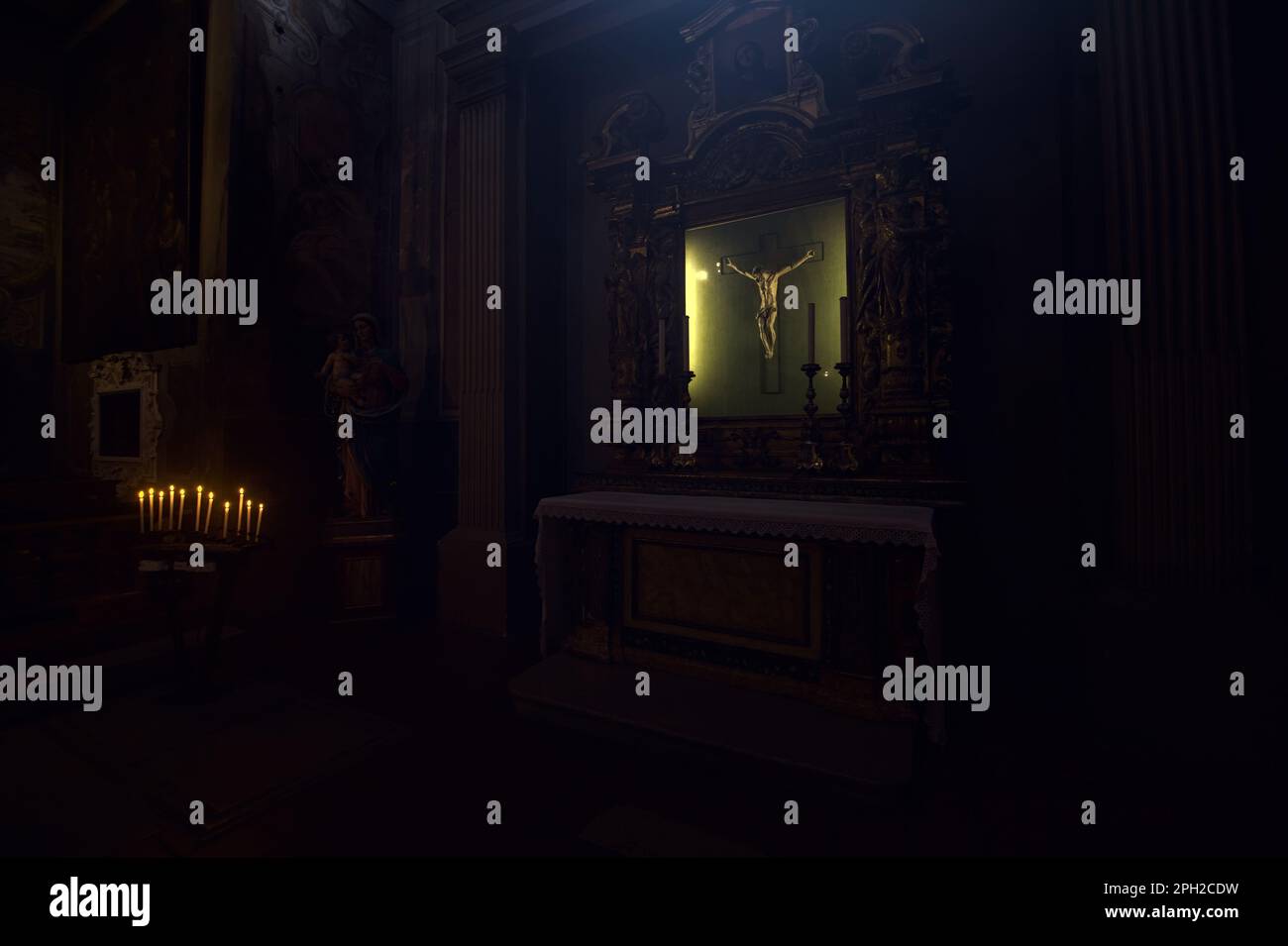 Crucified Christ in an illuminated display case over an altar in ...