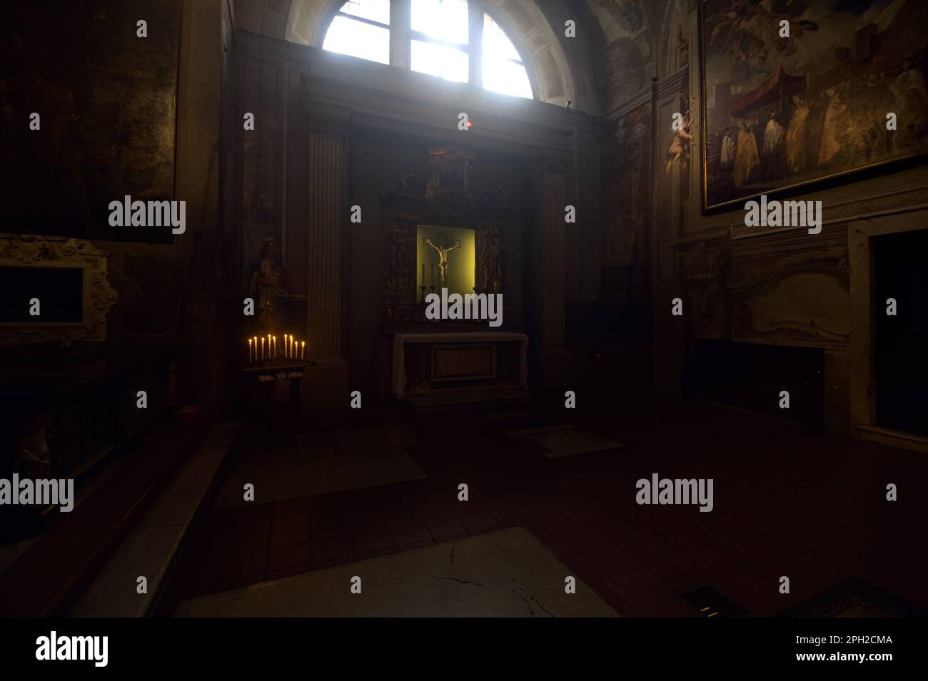 Crucified Christ in an illuminated display case over an altar in ...