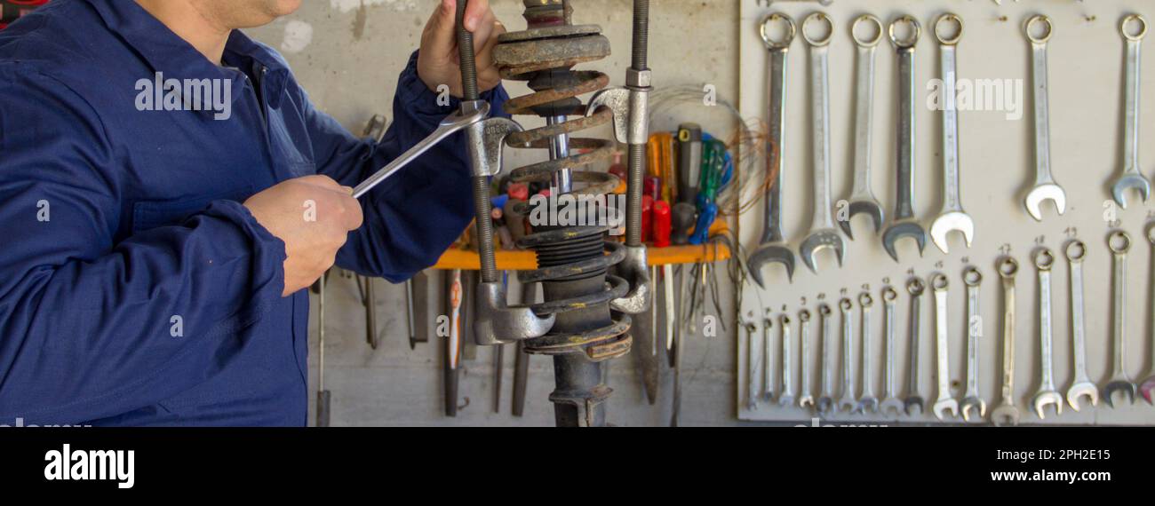 Image of a mechanic in overalls in his workshop while he disassembles a ...