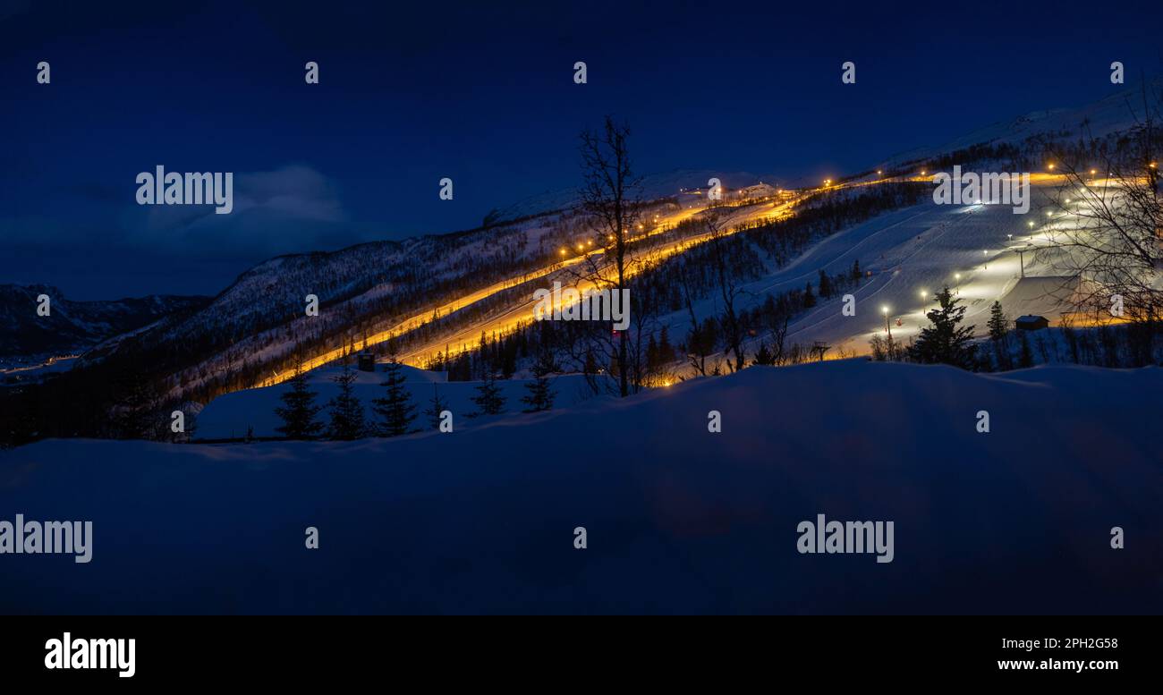 Night view over ski resort in lights and majestic snowy mountains ...