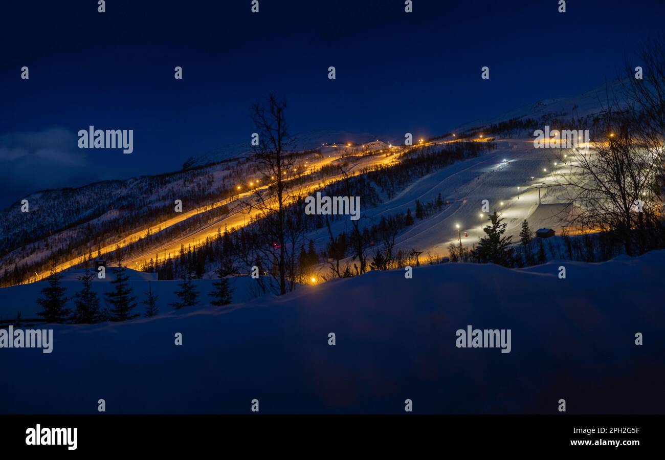 Night view over ski resort in lights and majestic snowy mountains ...