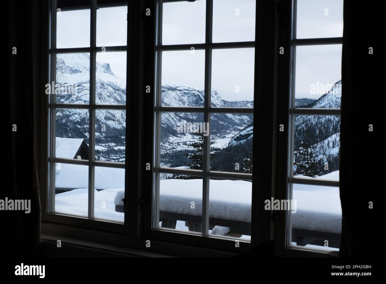 View through the window from cozy wooden cabin to snowy mountains ...