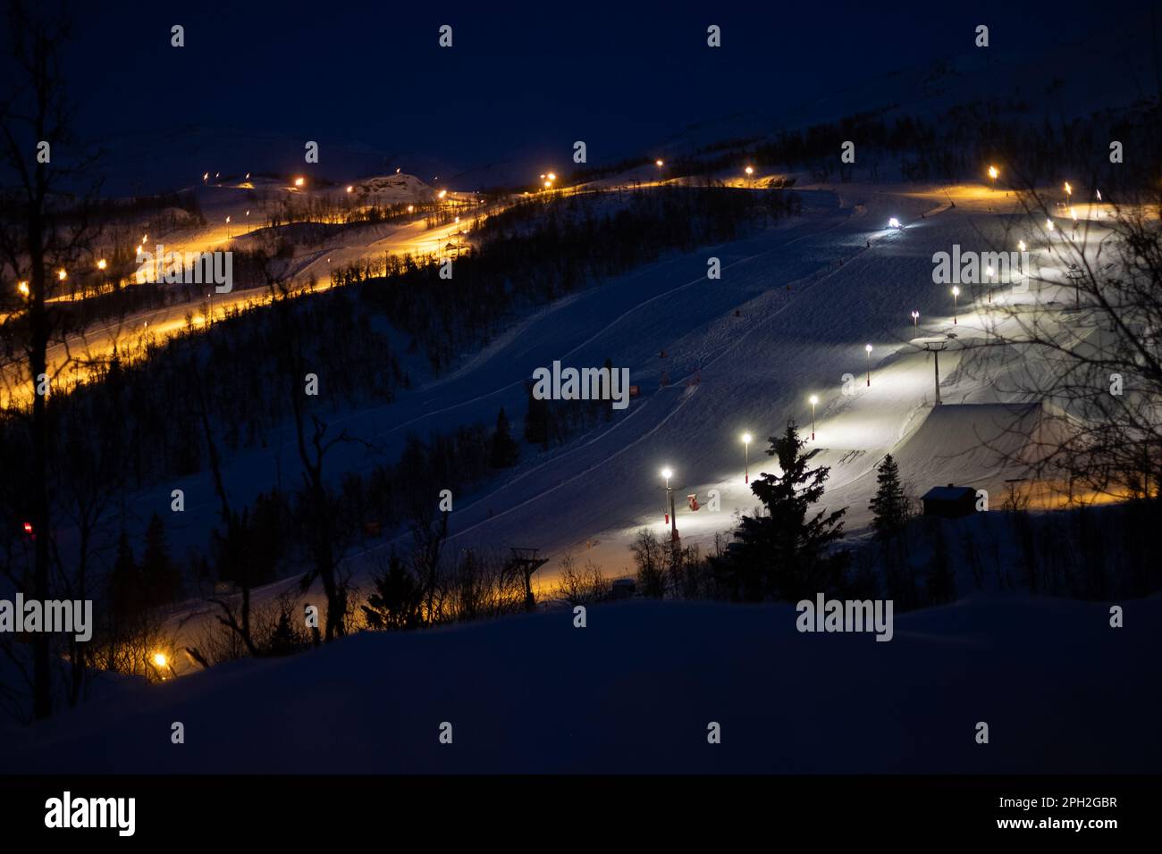 Night view over ski resort in lights and majestic snowy mountains ...