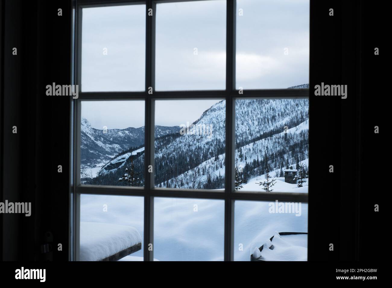 View through the window from cozy wooden cabin to snowy mountains ...