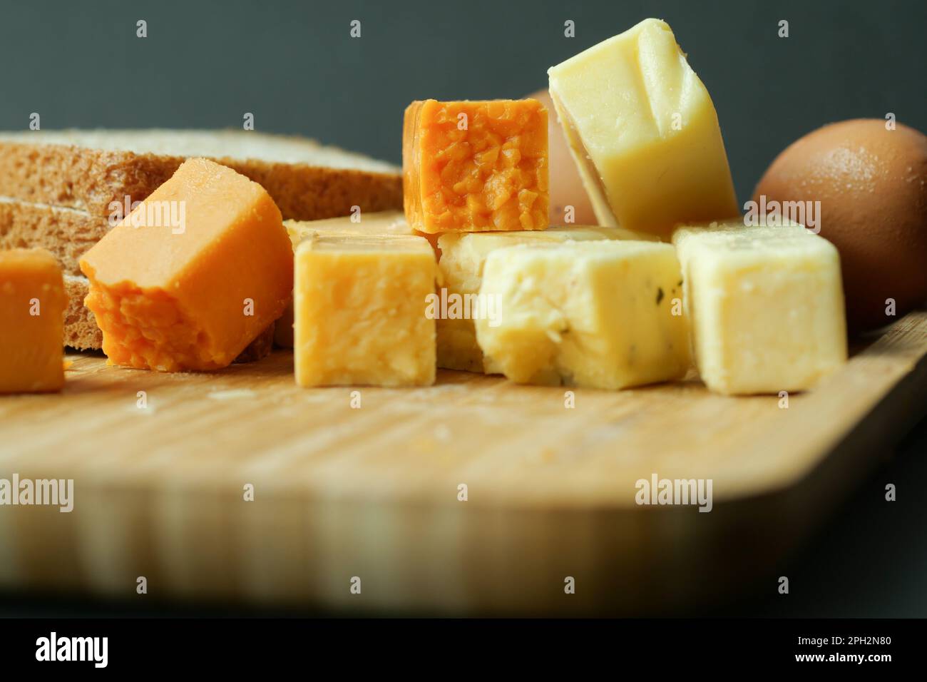 Cheese cubes green, yellow and red color on chopping board Stock Photo ...