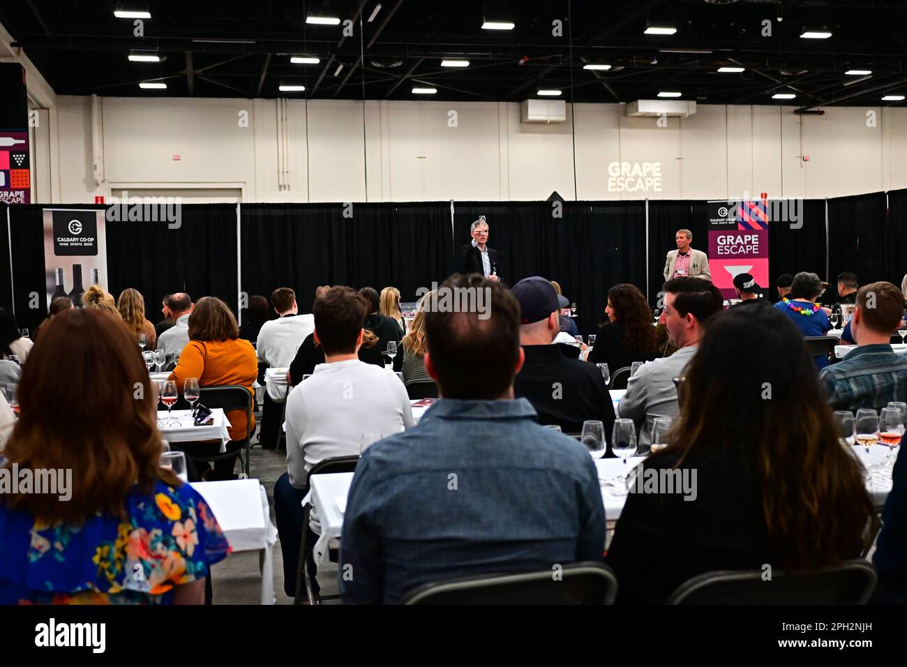 A group of people listens to a speaker during wine tasting seminar ...