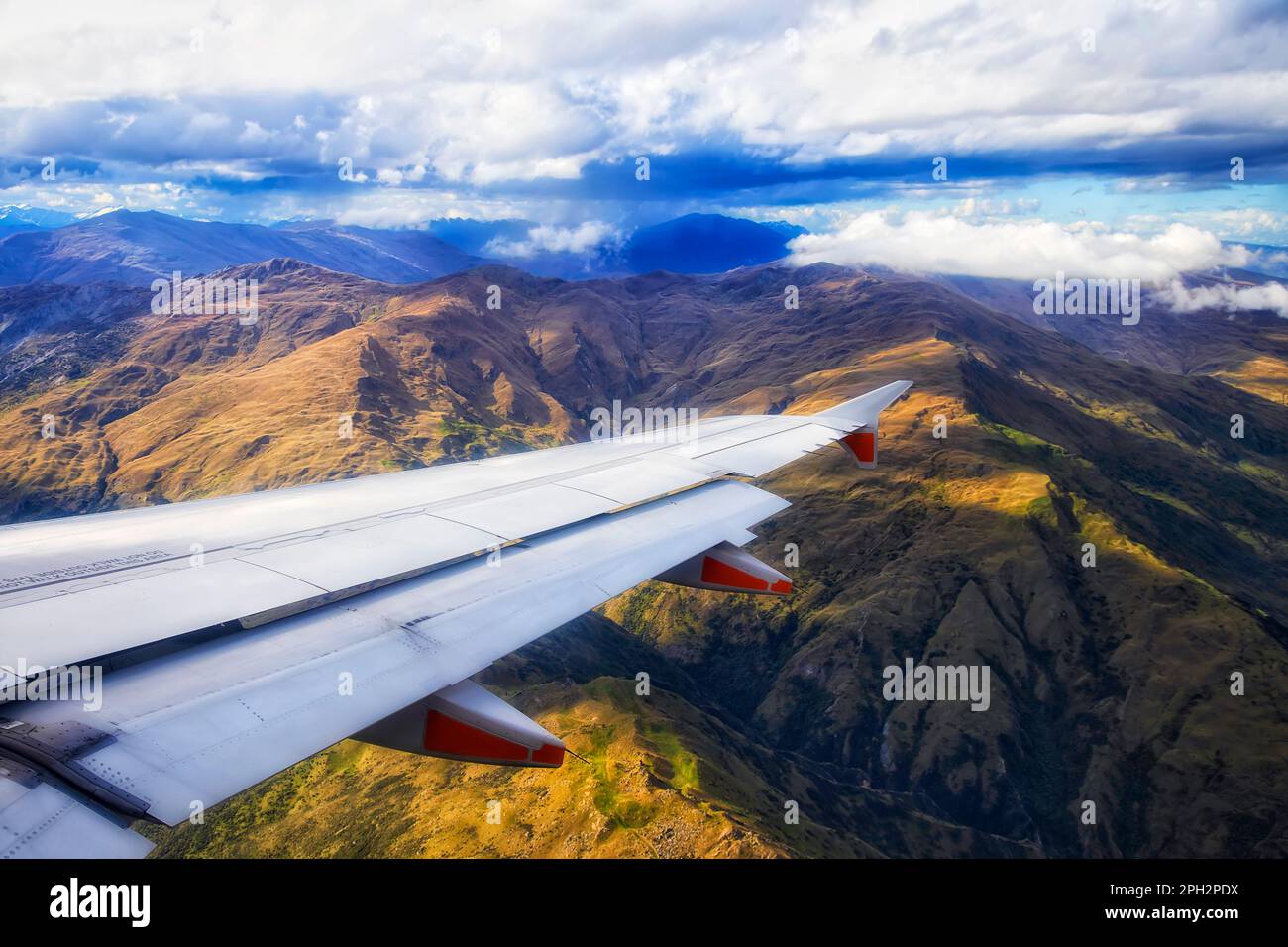 Mid-air passenter airplane flying over scenic mountains around ...