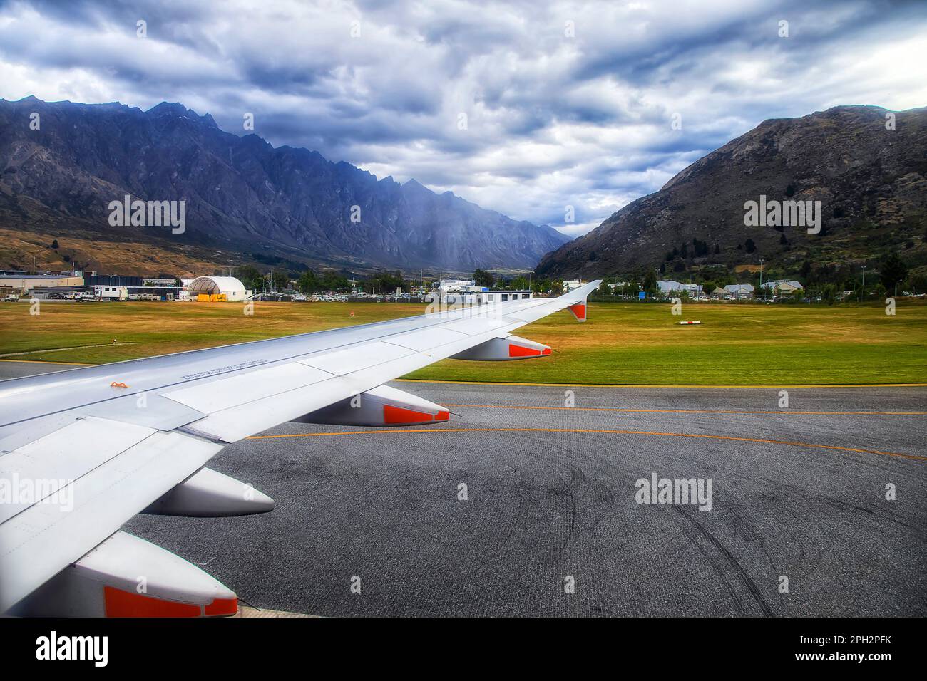Passenger airplane on runway of QUeenstown airport surrounded by scenic ...