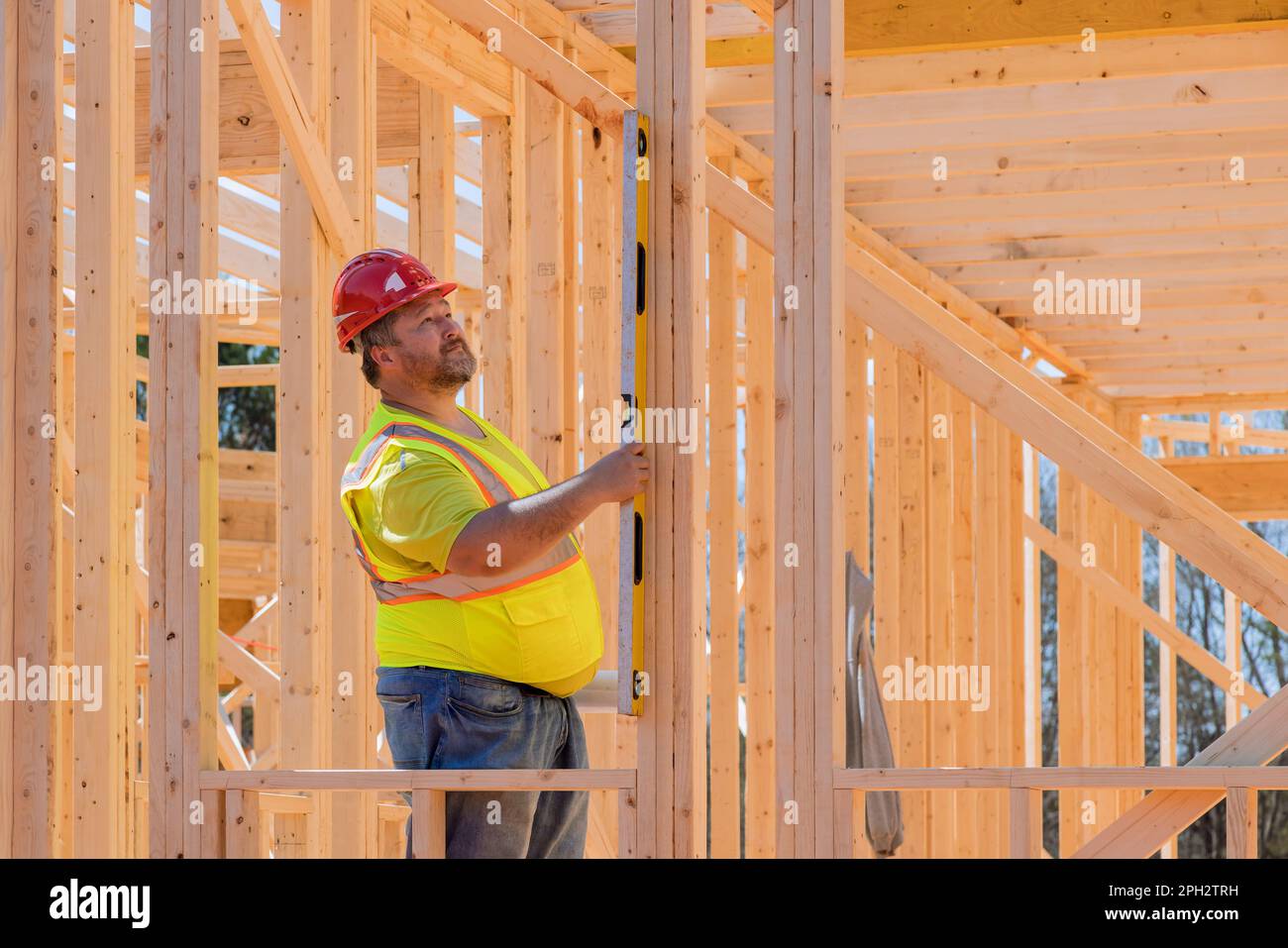 Construction engineer checking leveling quality of wooden frame beams ...