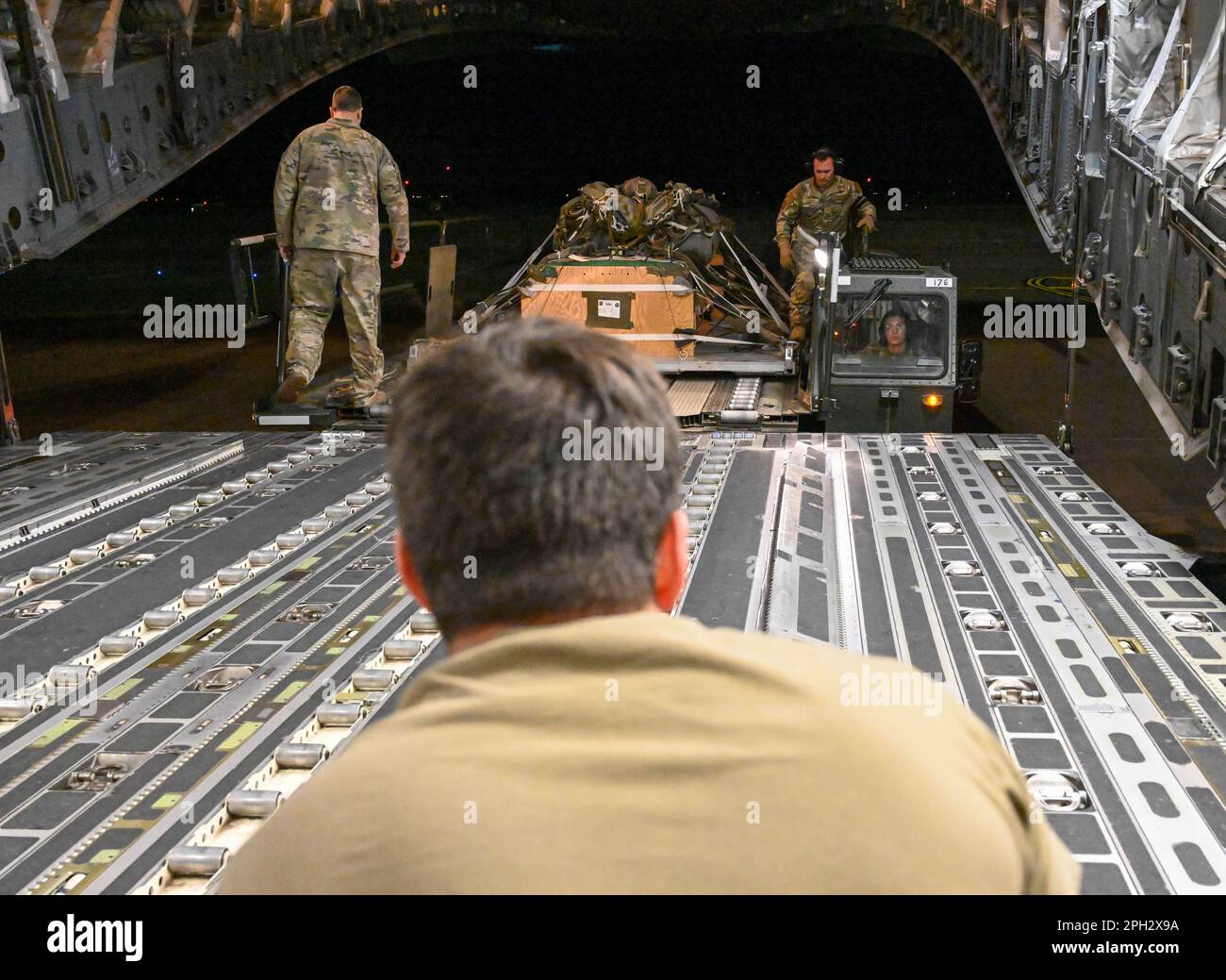 U.S. Air Force Airmen work together to guide a Tunner 60k loader near ...