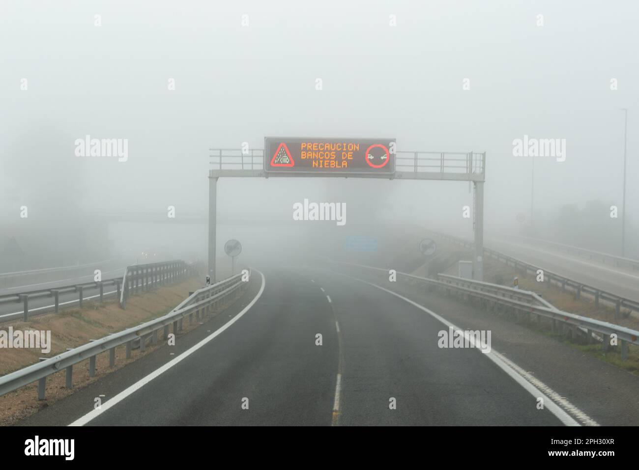 Illuminated sign on the highway with the legend Caution, fog banks ...