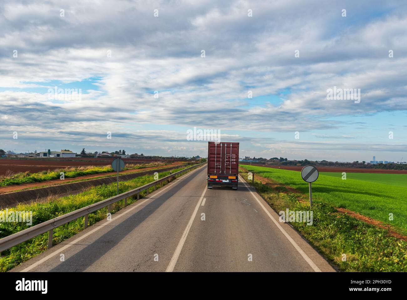 Truck with a container circulating on a conventional road next to ...