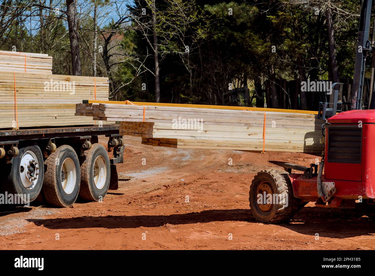 An operator of lift manipulator unloads wooden building material ...
