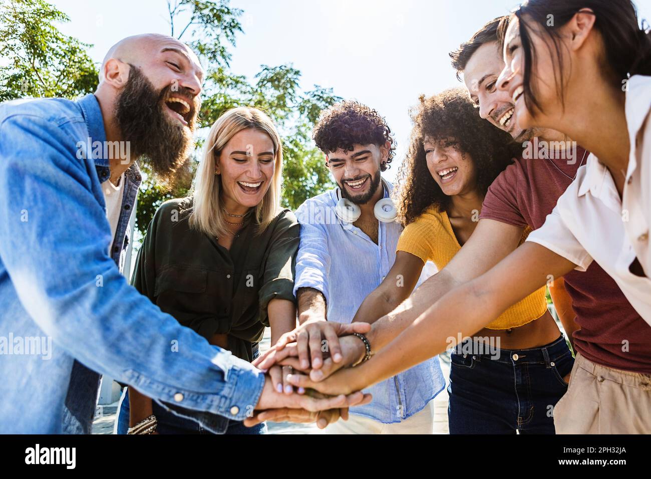 Multiracial young people stacking hands showing unity Stock Photo - Alamy