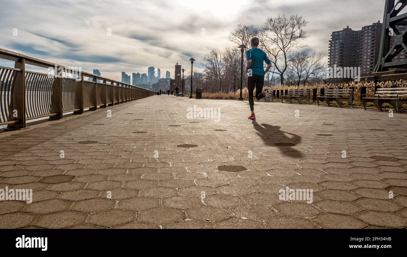 Runner jogging on the sidewalk next to the river in New York City Stock ...
