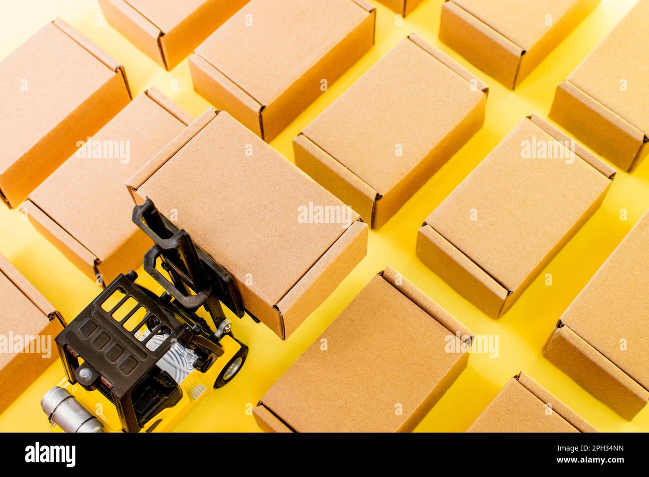 Forklift truck raises cardboard boxes on a yellow background. Cargo ...