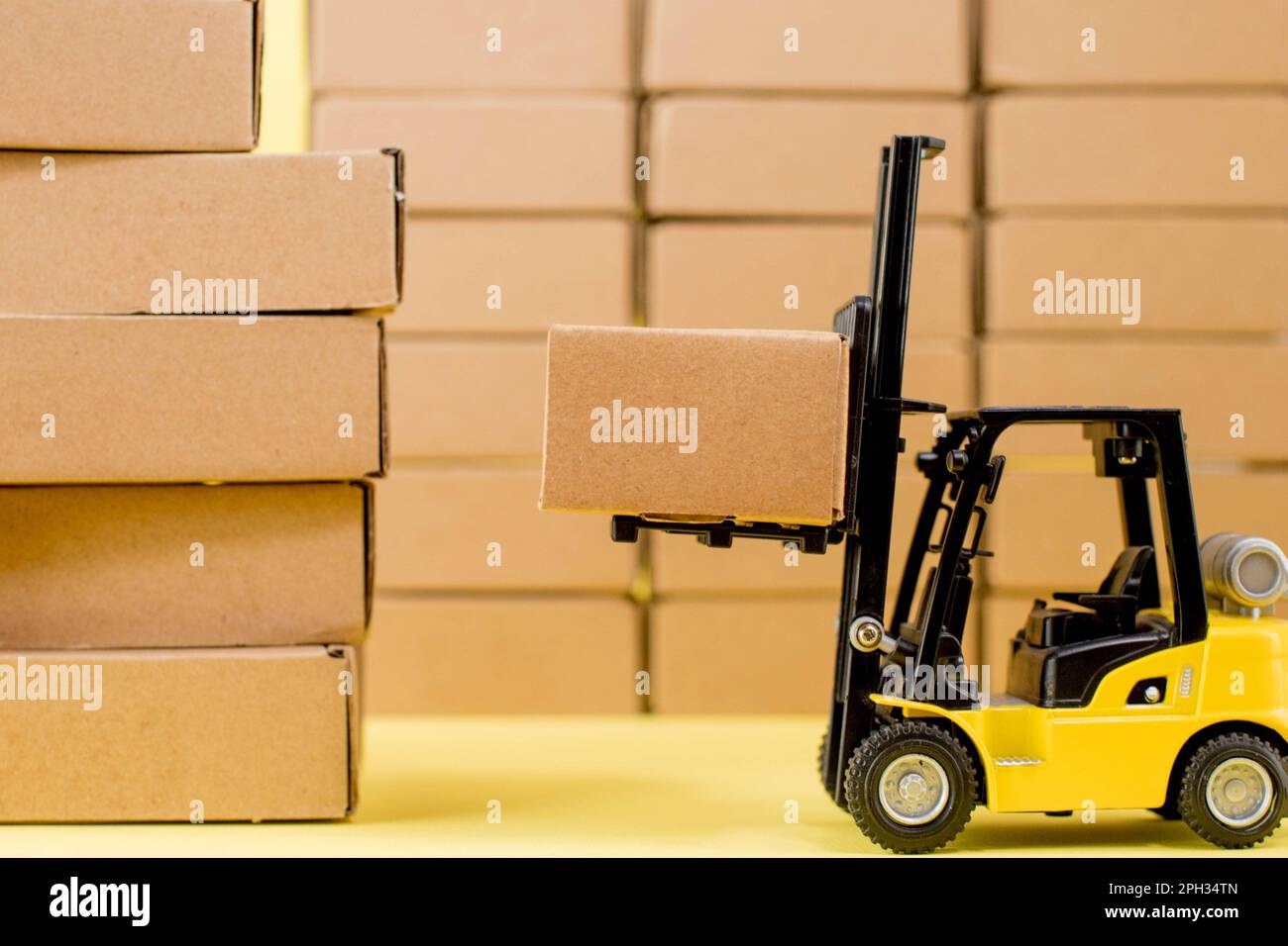 Forklift truck raises cardboard boxes on a yellow background. Cargo ...