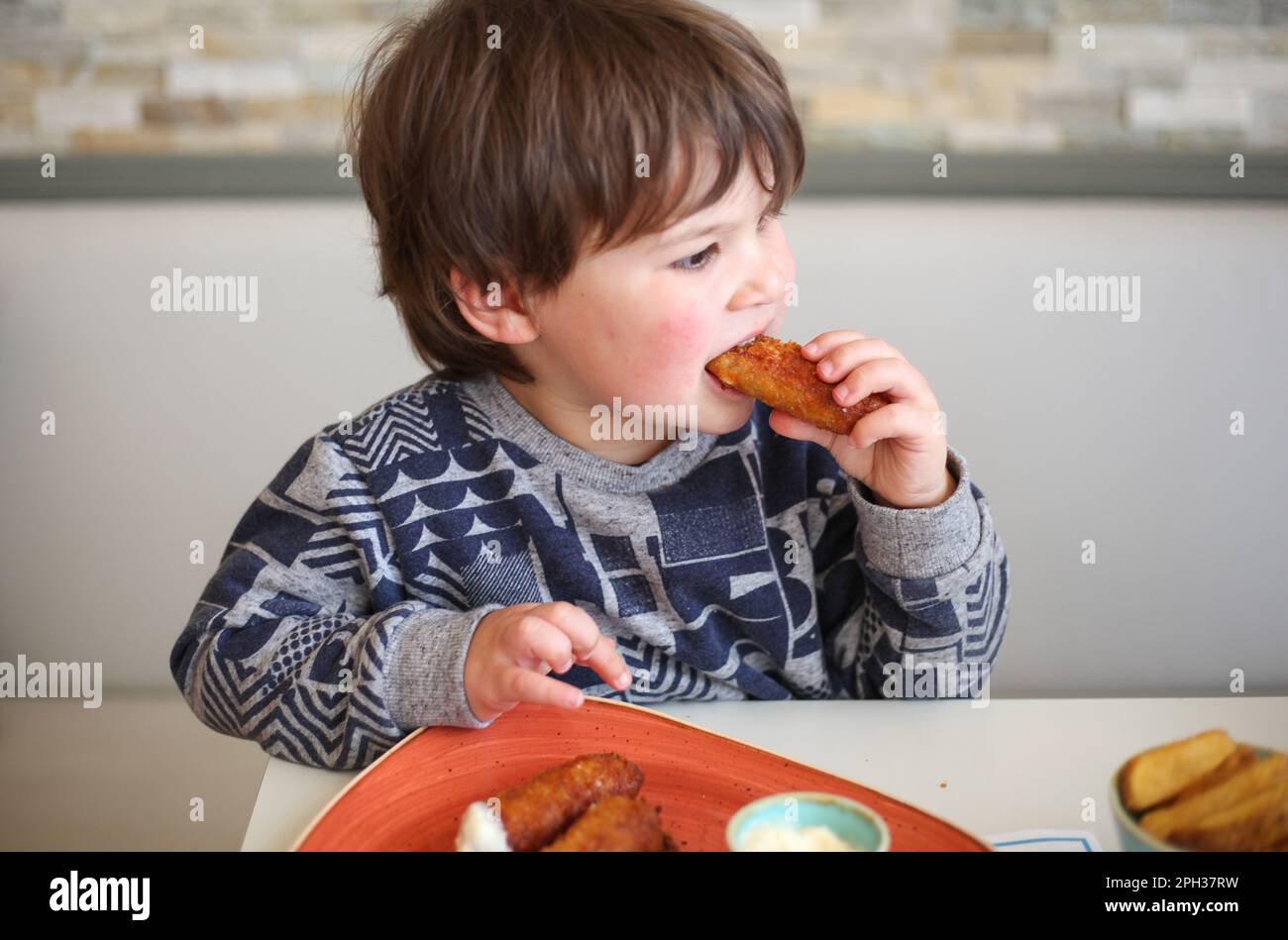Child eating fish fingers hi-res stock photography and images - Alamy