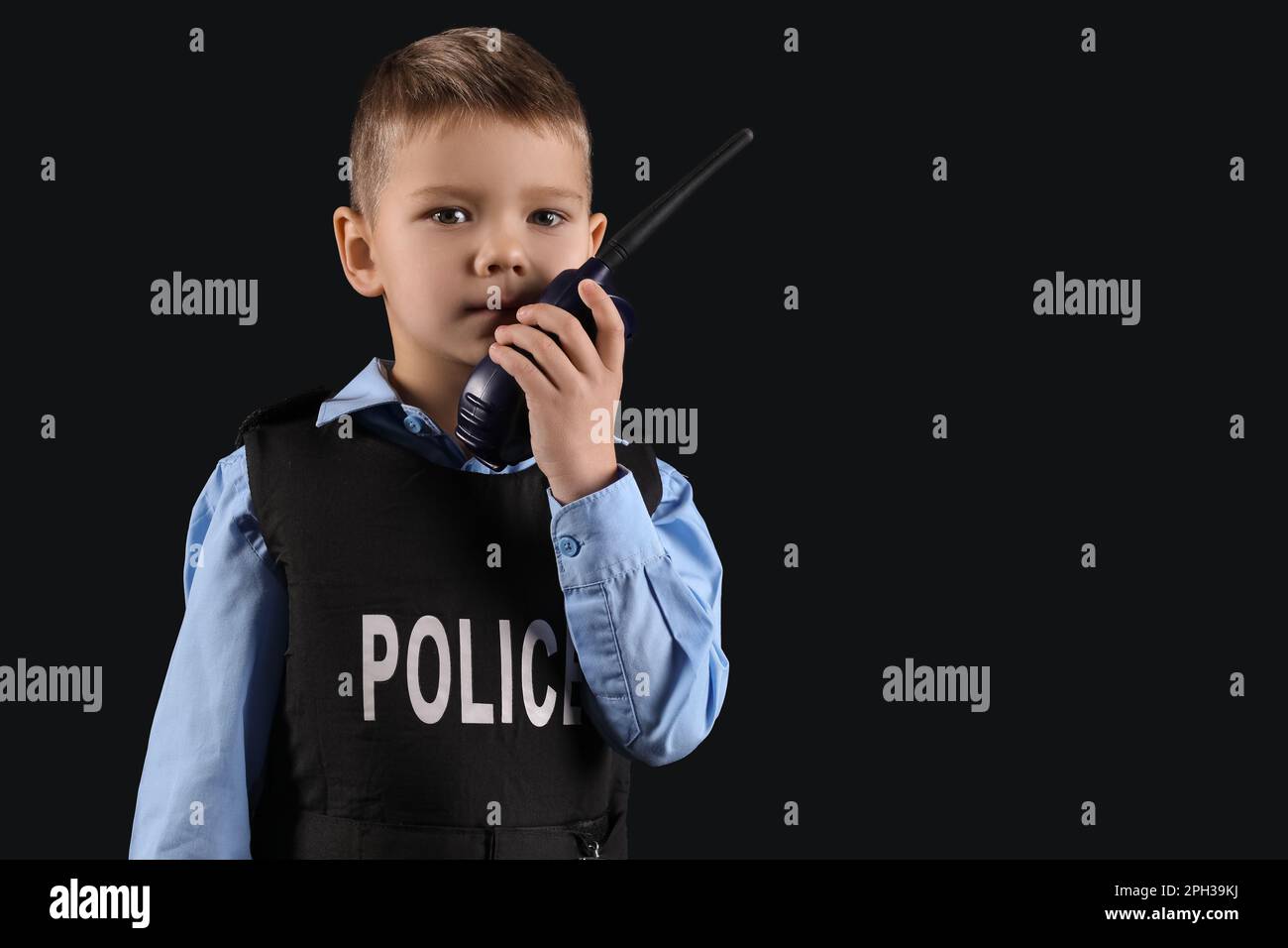 Cute little police officer with radio transmitter on black background ...