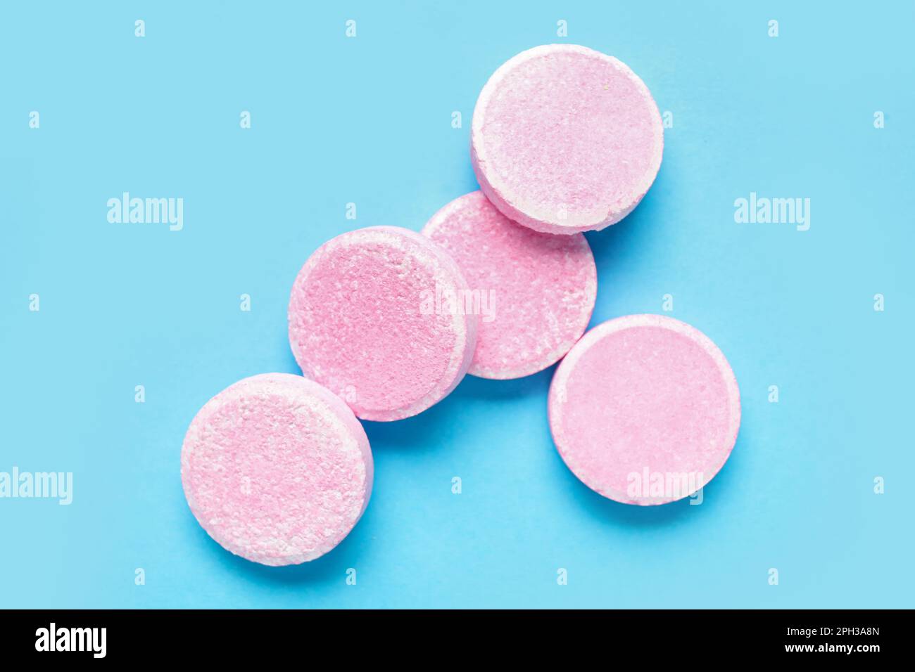 Pink soluble tablets on blue background Stock Photo - Alamy