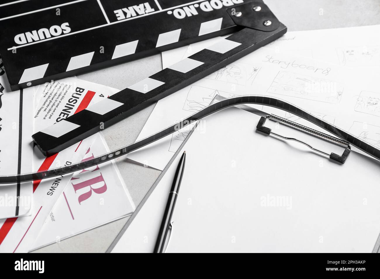 Clipboard with film, newspapers and movie clapper on light background ...