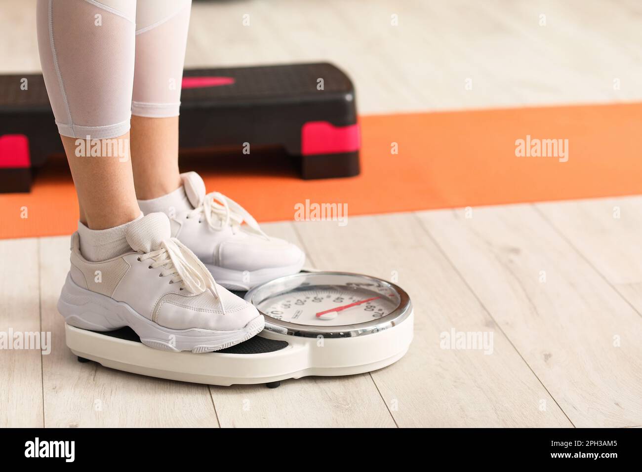 Sporty young woman measuring her weight on scales in gym, closeup Stock ...