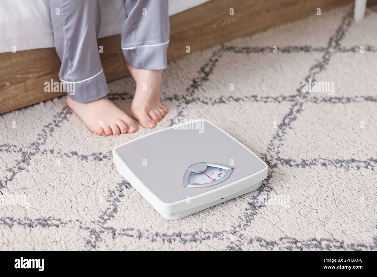 Young woman measuring her weight with scales in bedroom, closeup Stock ...
