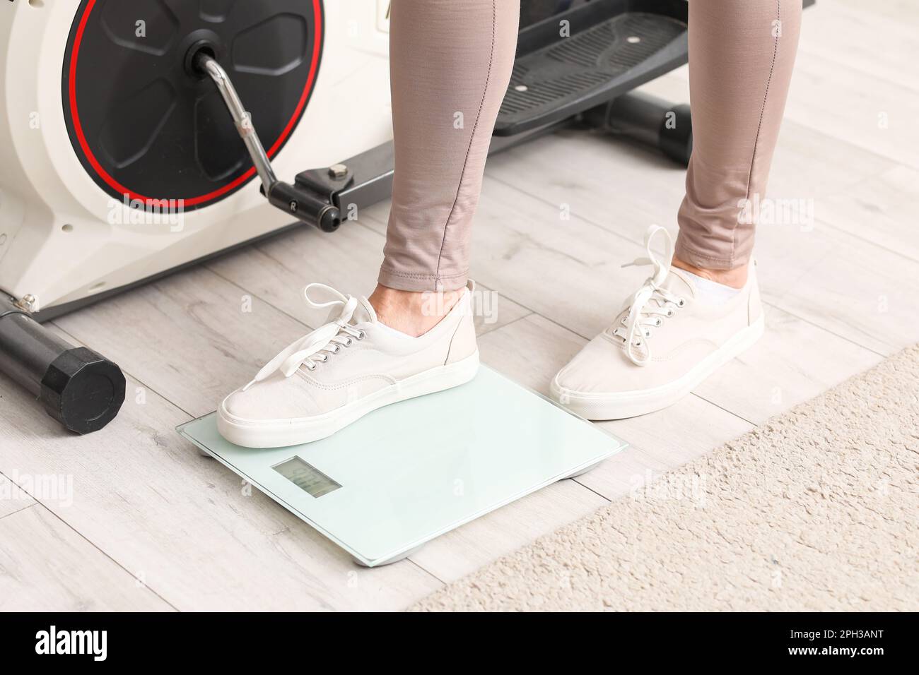 Sporty mature woman measuring her weight on scales at home, closeup ...