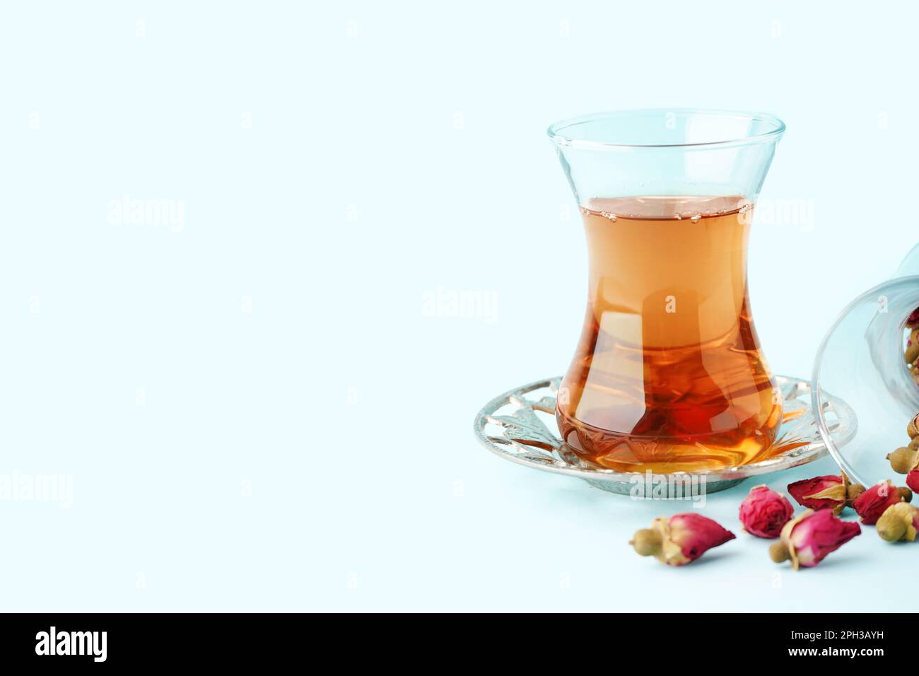 Glass of Turkish tea and dry roses on light blue background Stock Photo ...