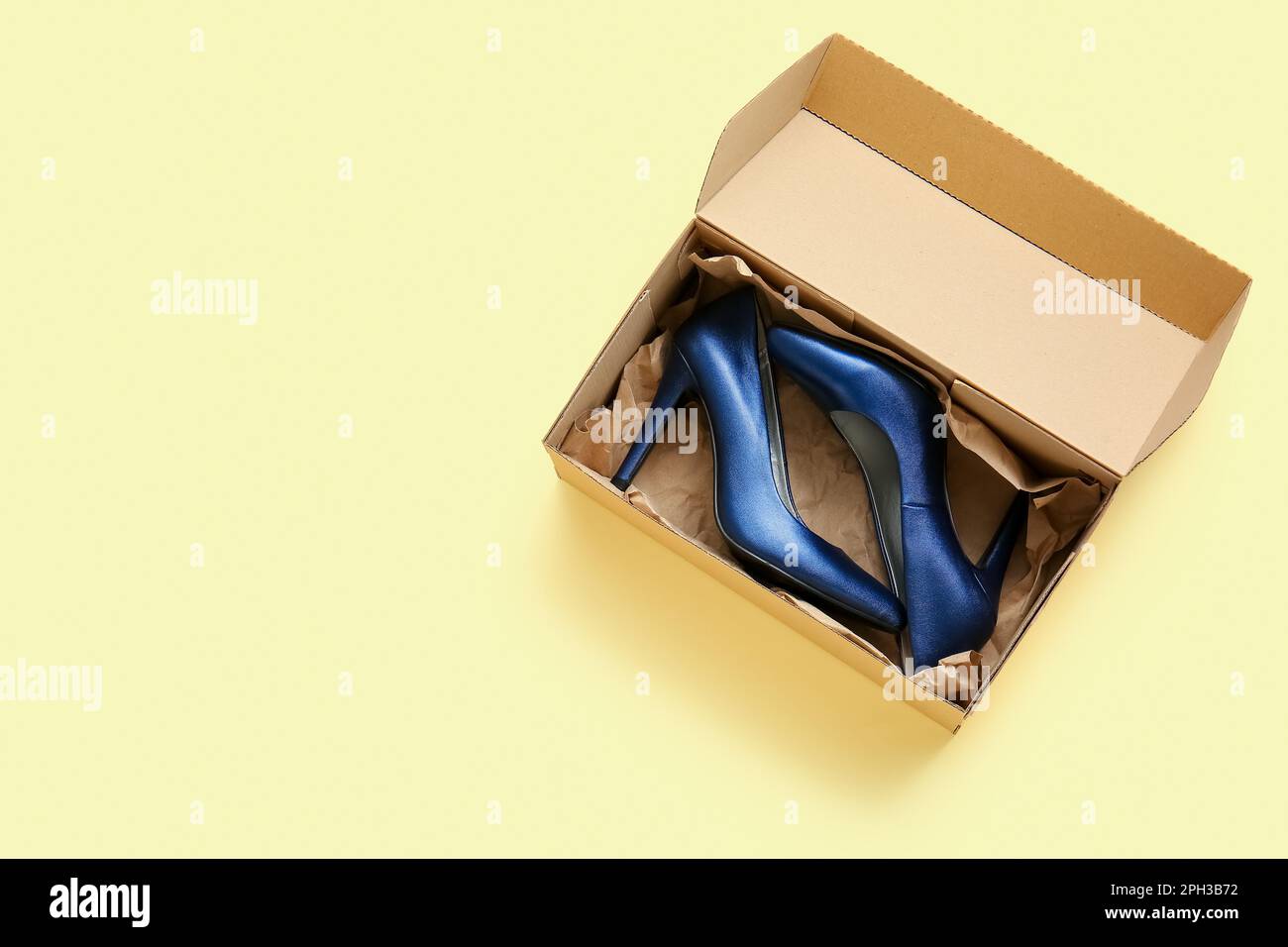 Cardboard box with high heeled shoes on beige background Stock Photo ...