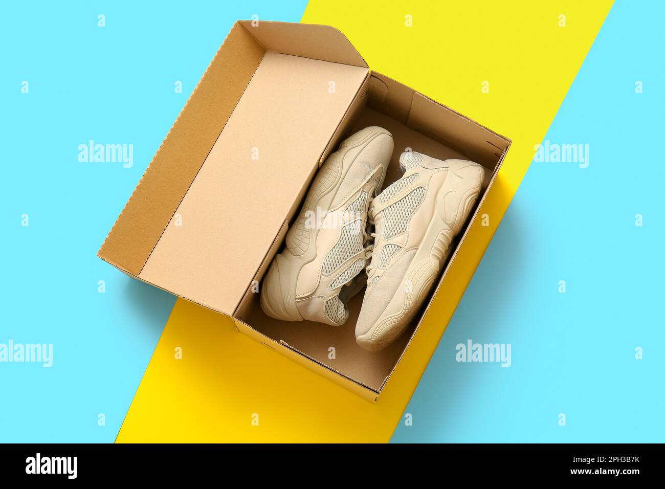 Cardboard box with sports shoes on color background Stock Photo - Alamy