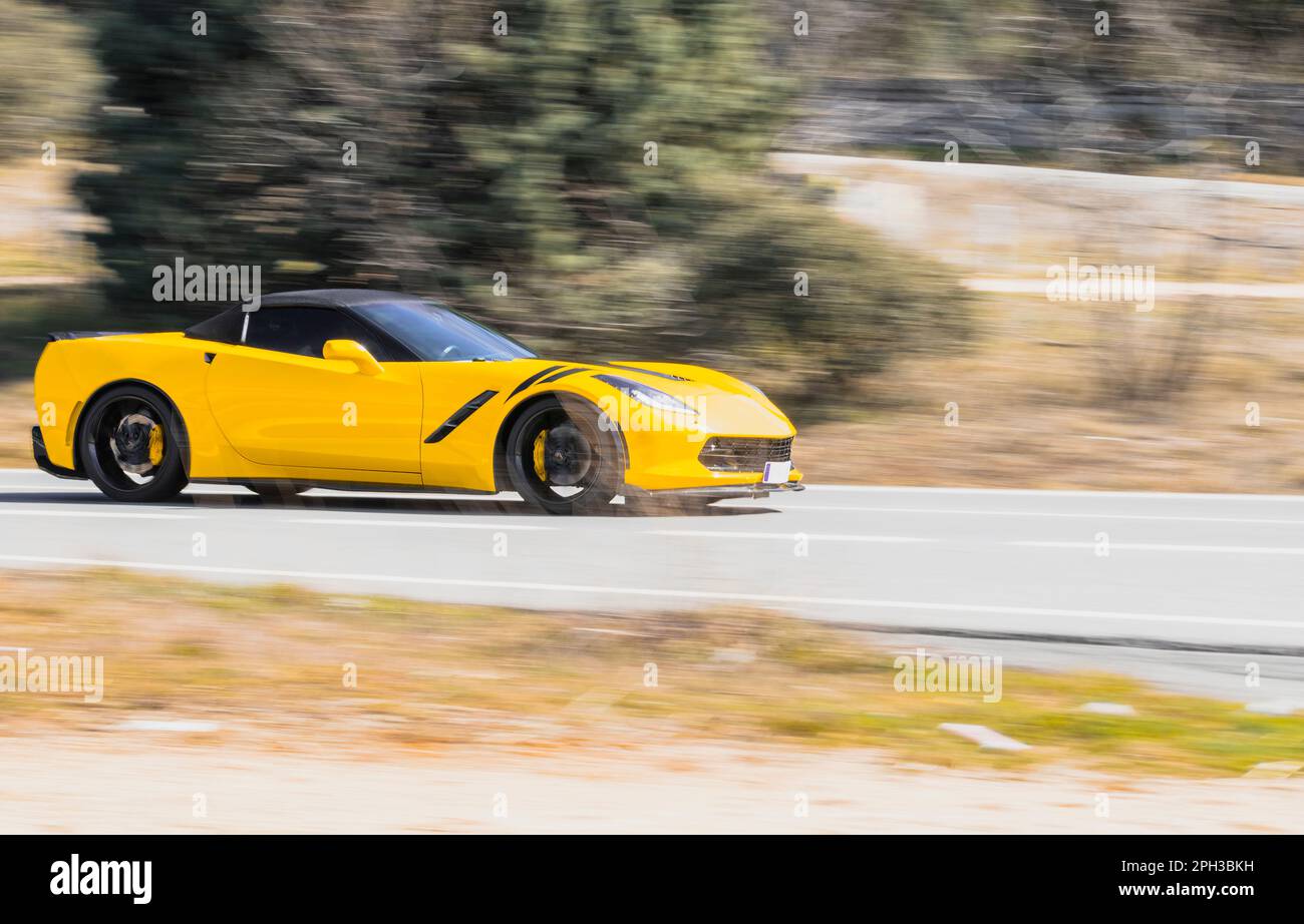 Yellow luxury sports car, driving at high speed on the road by day ...