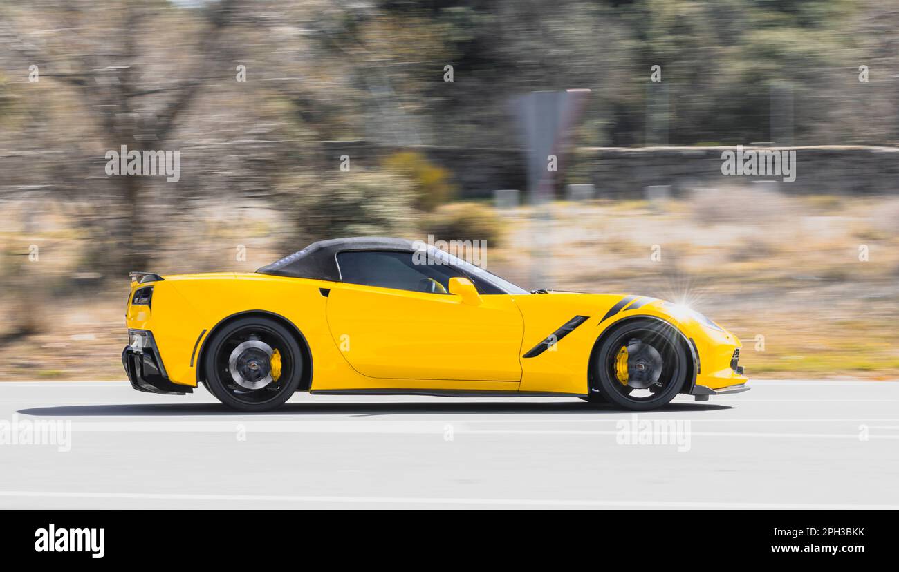 Yellow luxury sports car, driving at high speed on the road by day ...
