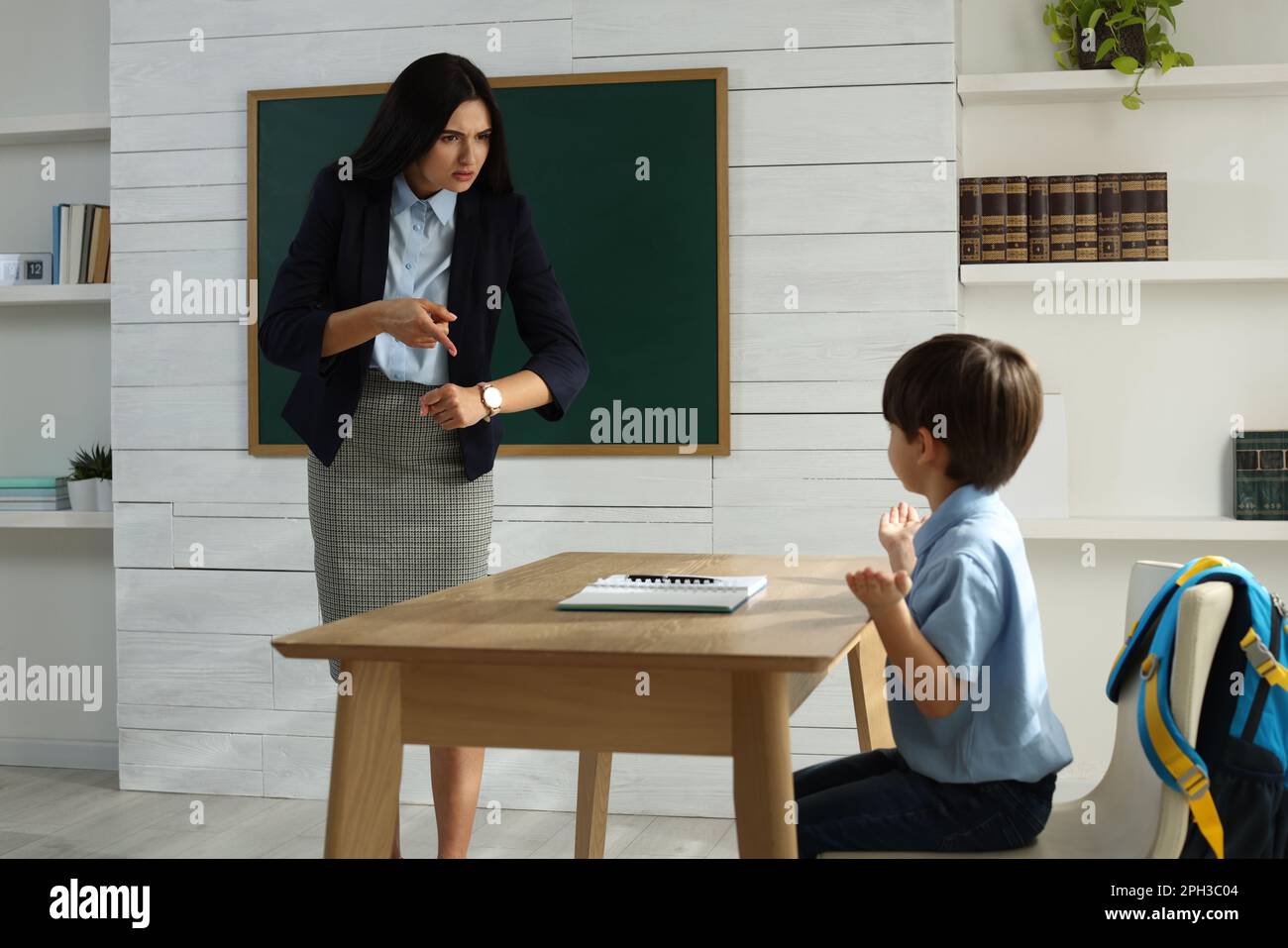Teacher pointing on wrist watch while scolding pupil for being late in ...