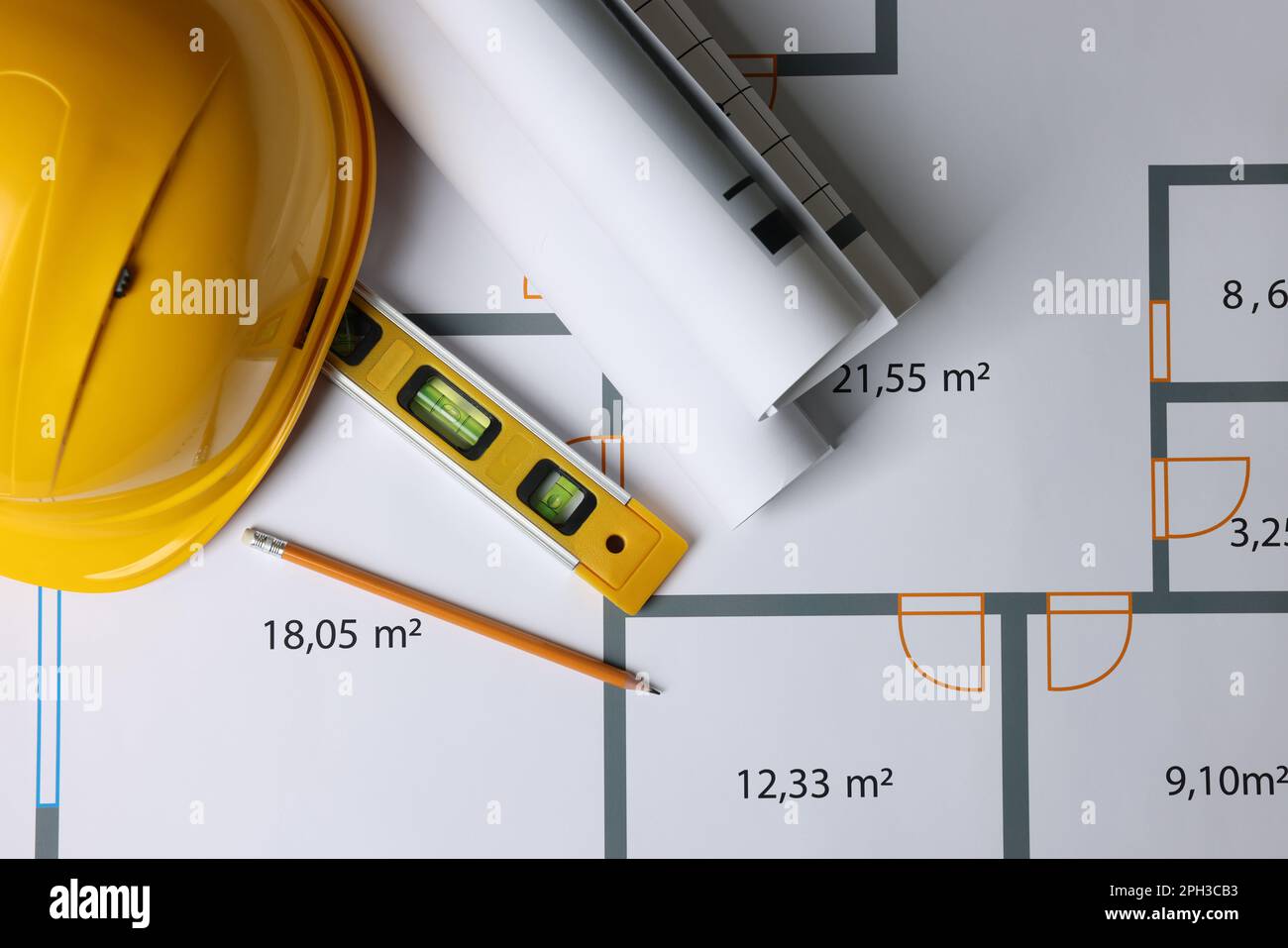 Rolled construction drawings, safety hat, pencil and bubble level on ...