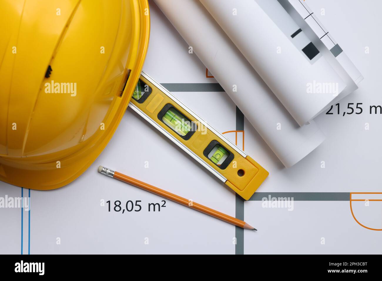 Rolled construction drawings, safety hat, pencil and bubble level on ...